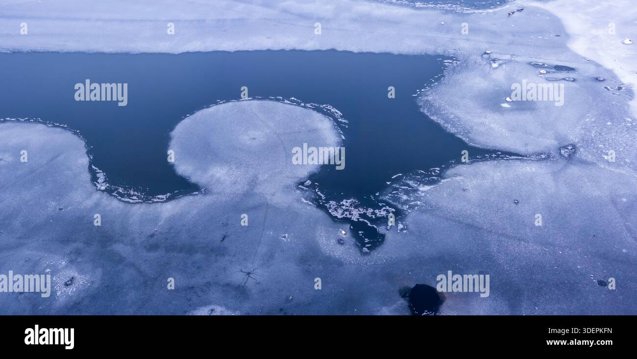 Aerial view capturing a partially frozen river with irregular shapes of ...