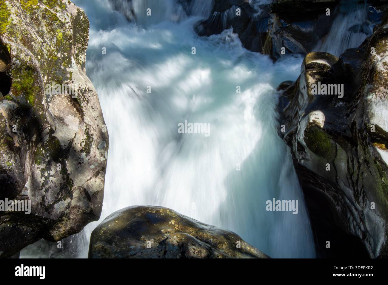 A close-up view of a rushing waterfall cascading over smooth, dark ...