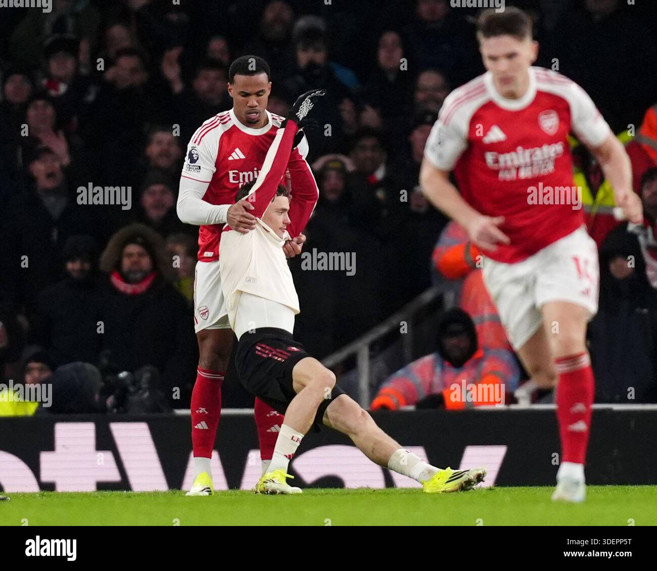 Liverpool's Florian Wirtz reacts as Arsenal's Gabriel helps him to his ...