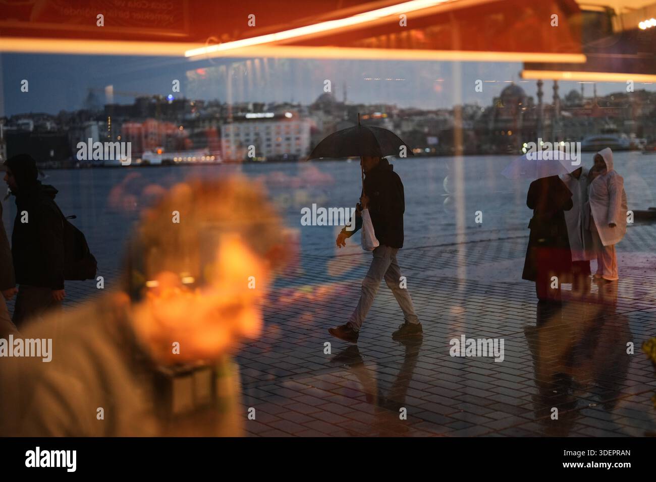 A man using an umbrella walks past on a rainy winter day in Istanbul ...