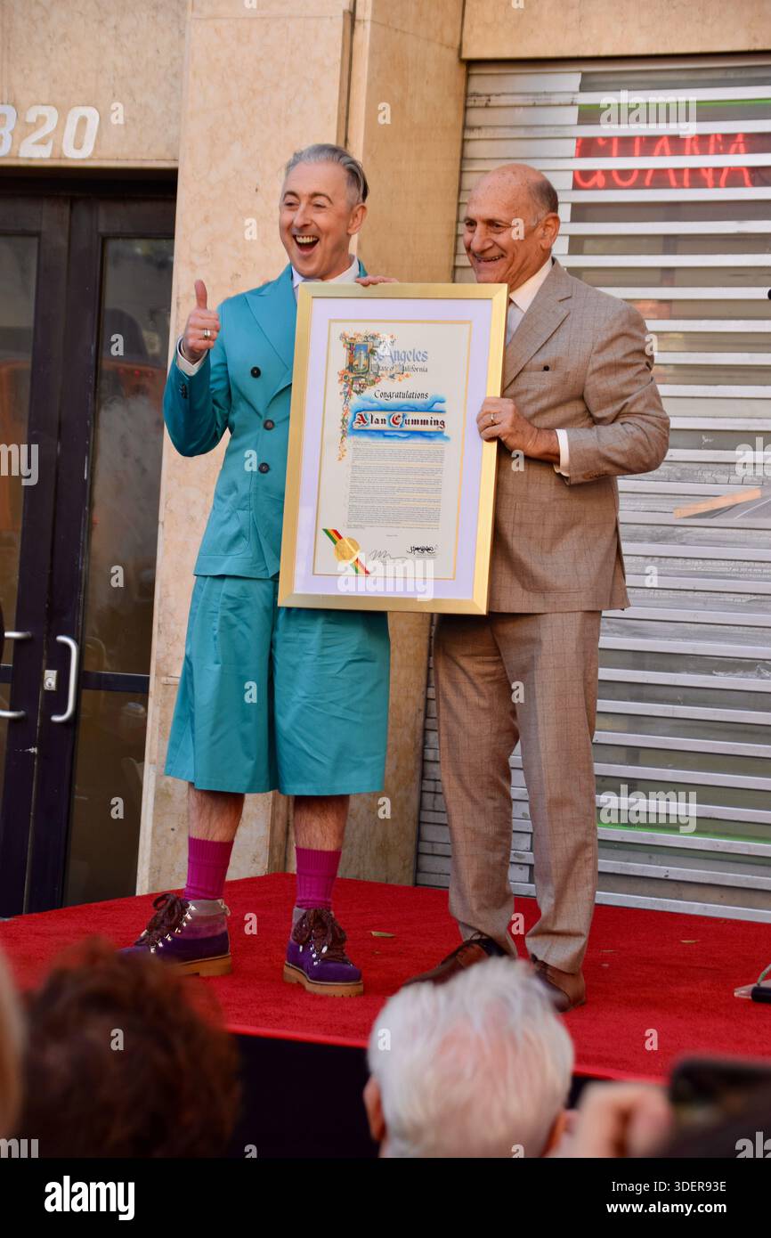 Alan Cumming gives a thumbs up while holding a proclamation with Steve ...