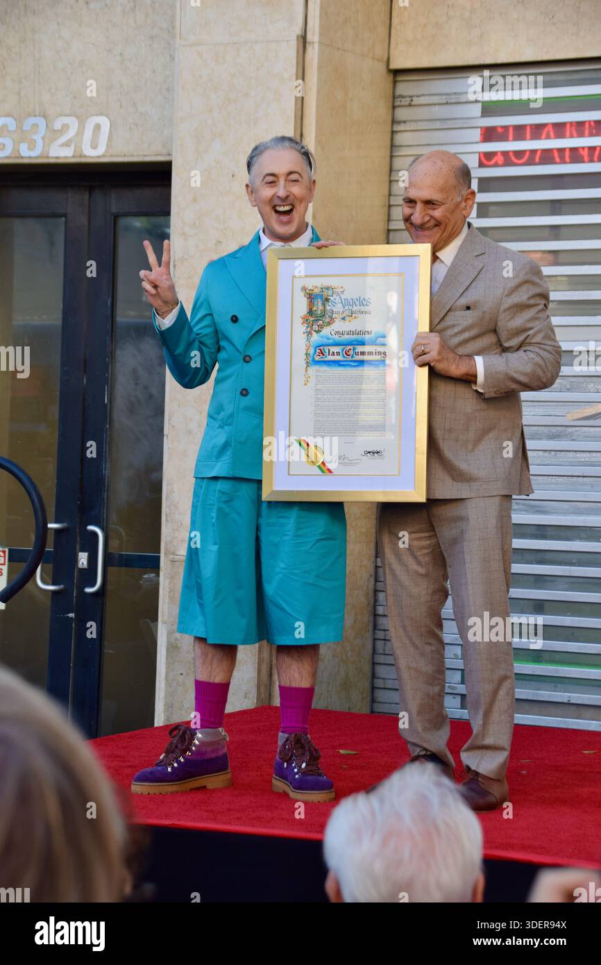Alan Cumming flashes a peace sign while holding a proclamation with ...