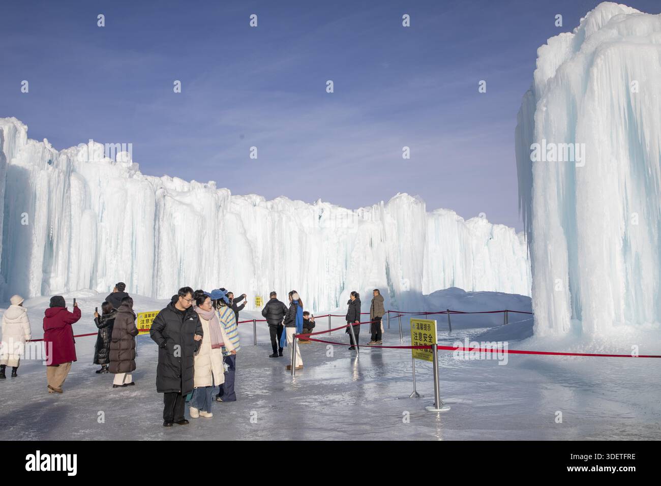 Tourists visit the blue ice waterfalls formed by frozen lake water at ...