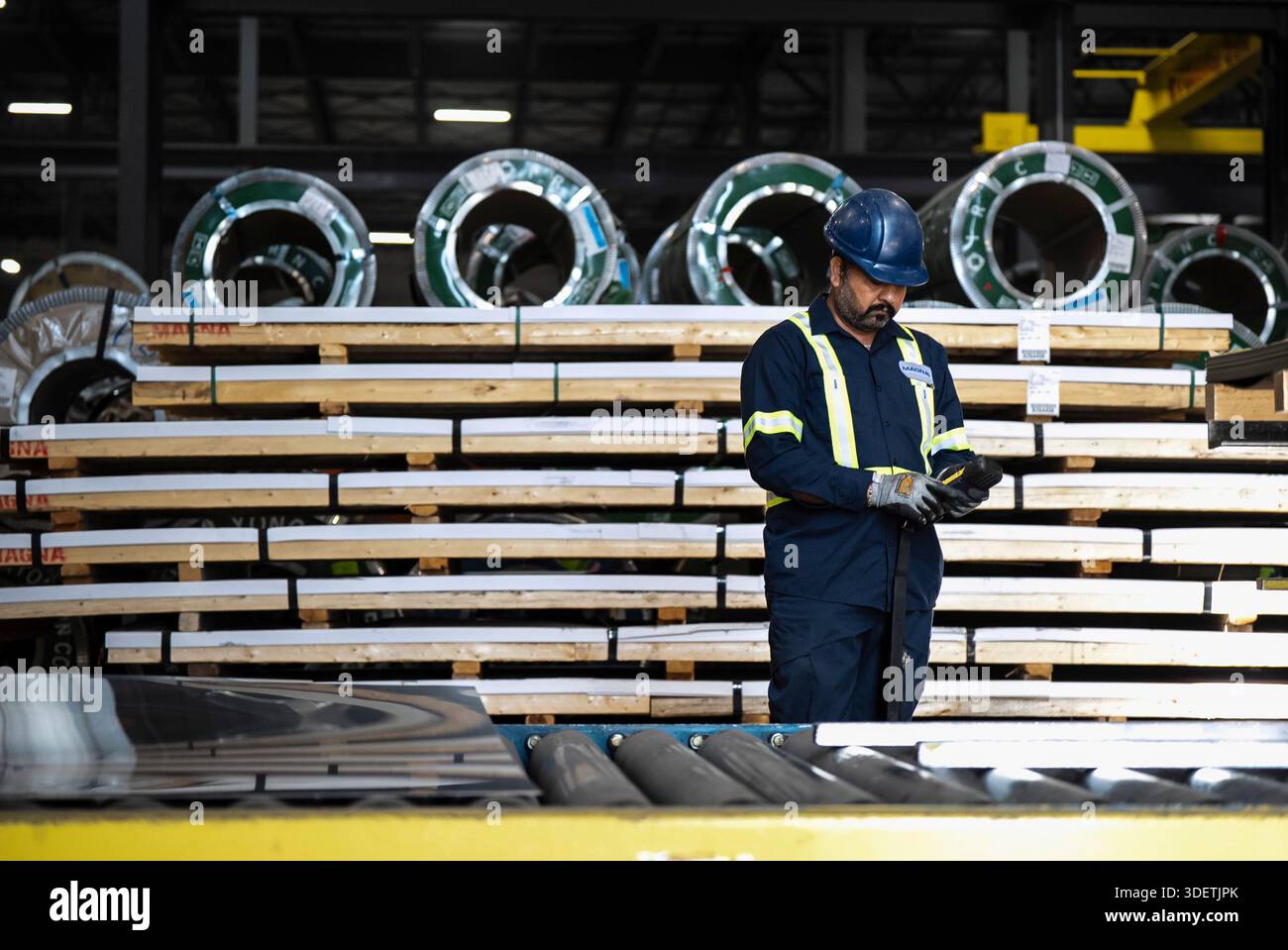 Workers inspect sheets of stainless steel after being pressed from ...