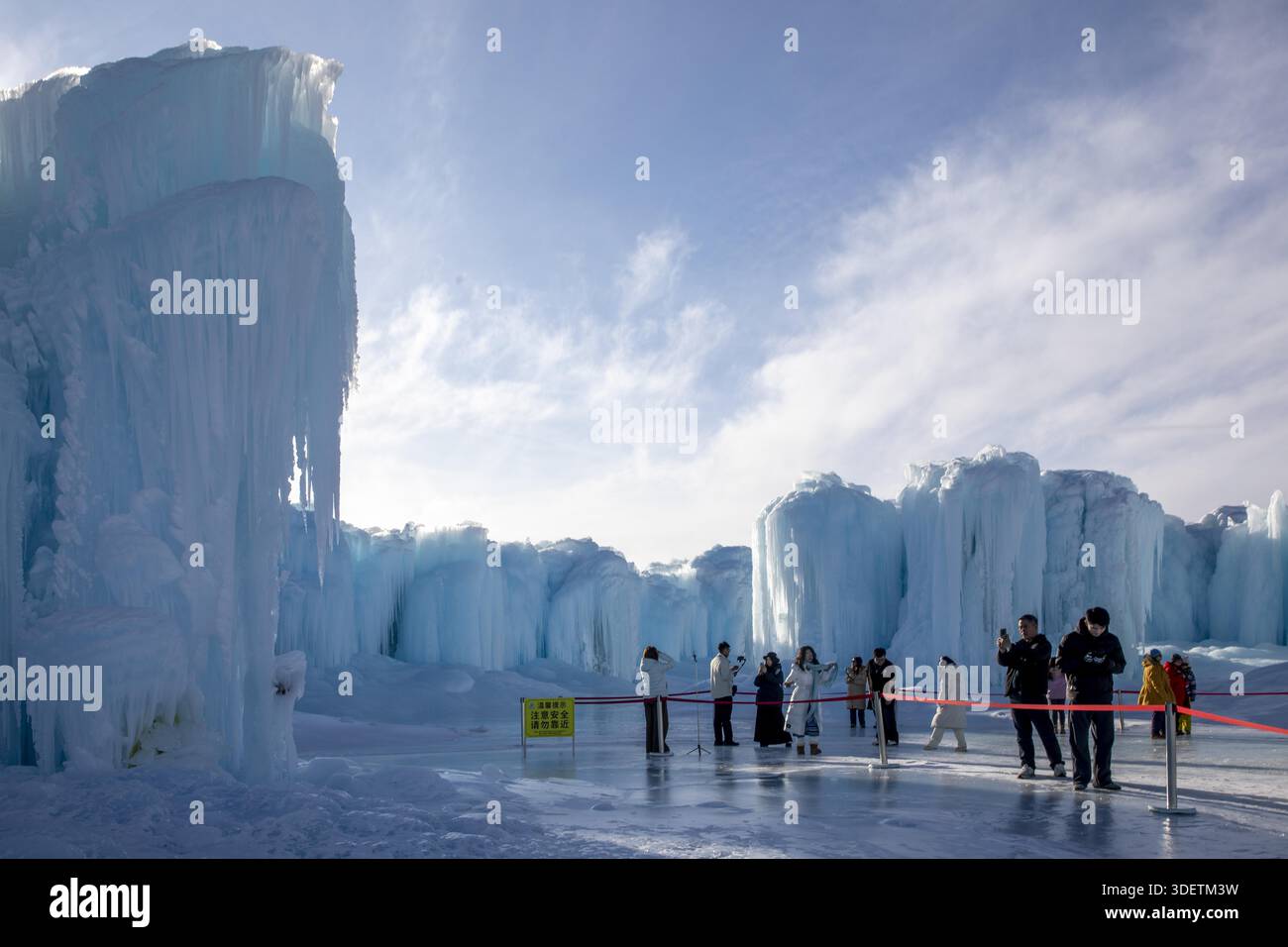Tourists visit the blue ice waterfalls formed by frozen lake water at ...