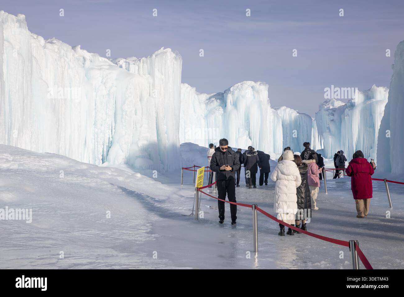 Tourists visit the blue ice waterfalls formed by frozen lake water at ...