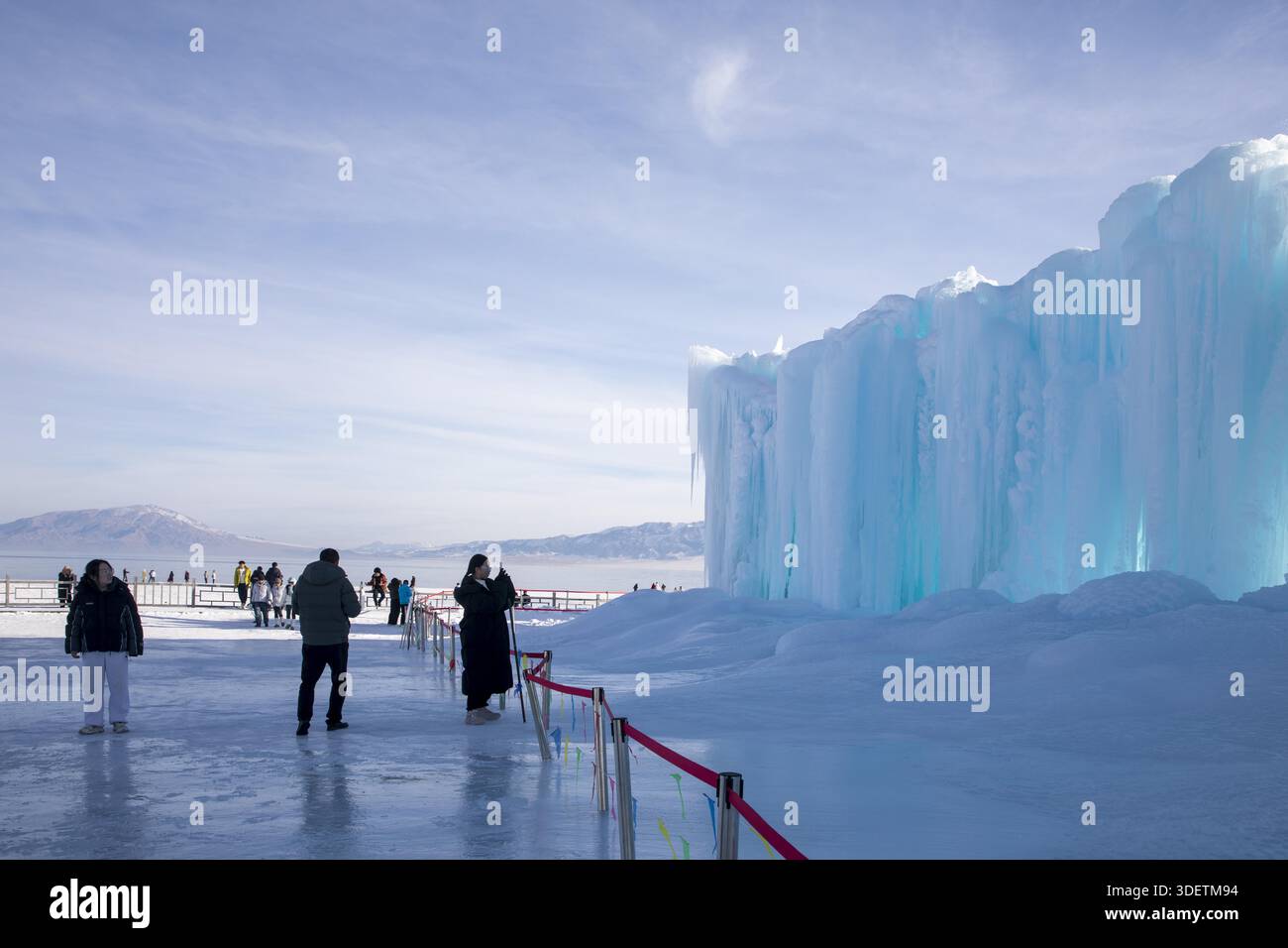 Tourists visit the blue ice waterfalls formed by frozen lake water at ...