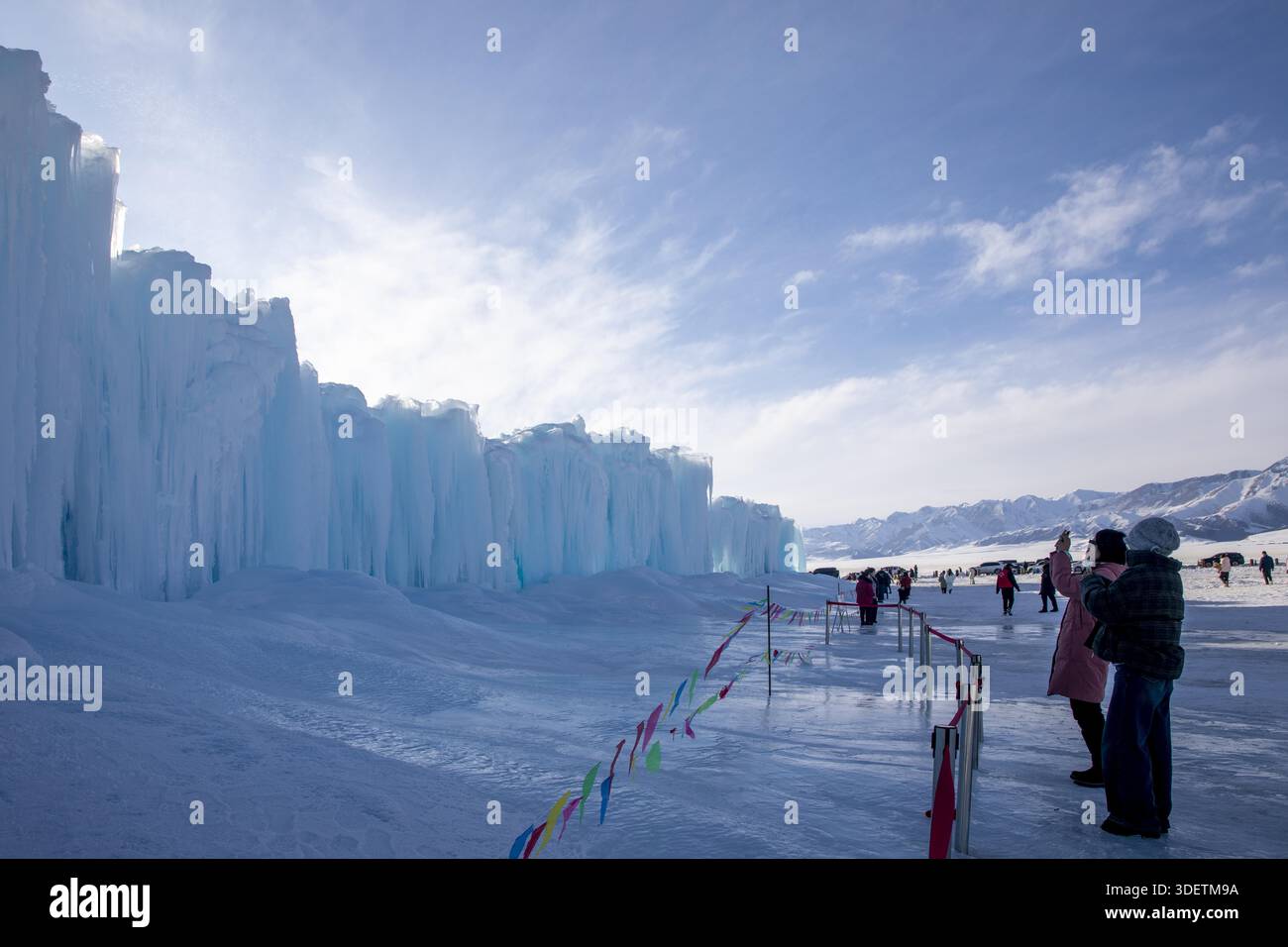 Tourists visit the blue ice waterfalls formed by frozen lake water at ...