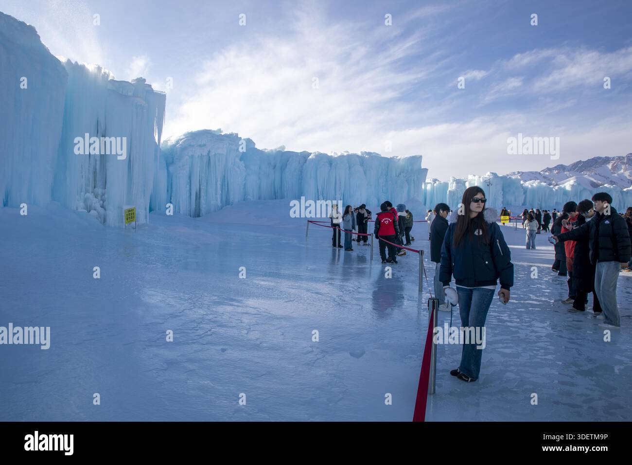 Tourists visit the blue ice waterfalls formed by frozen lake water at ...