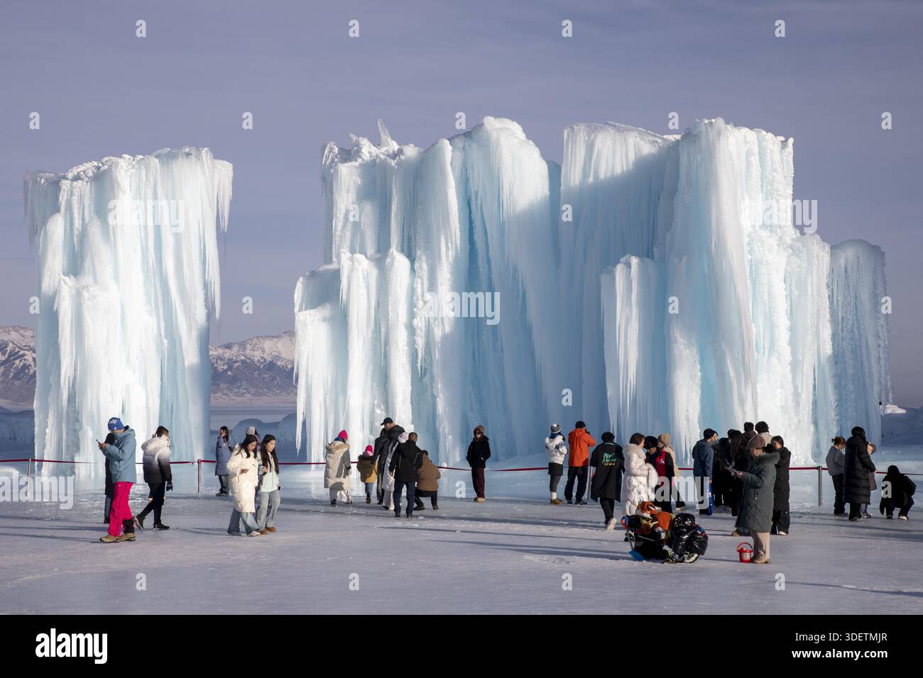 Tourists visit the blue ice waterfalls formed by frozen lake water at ...