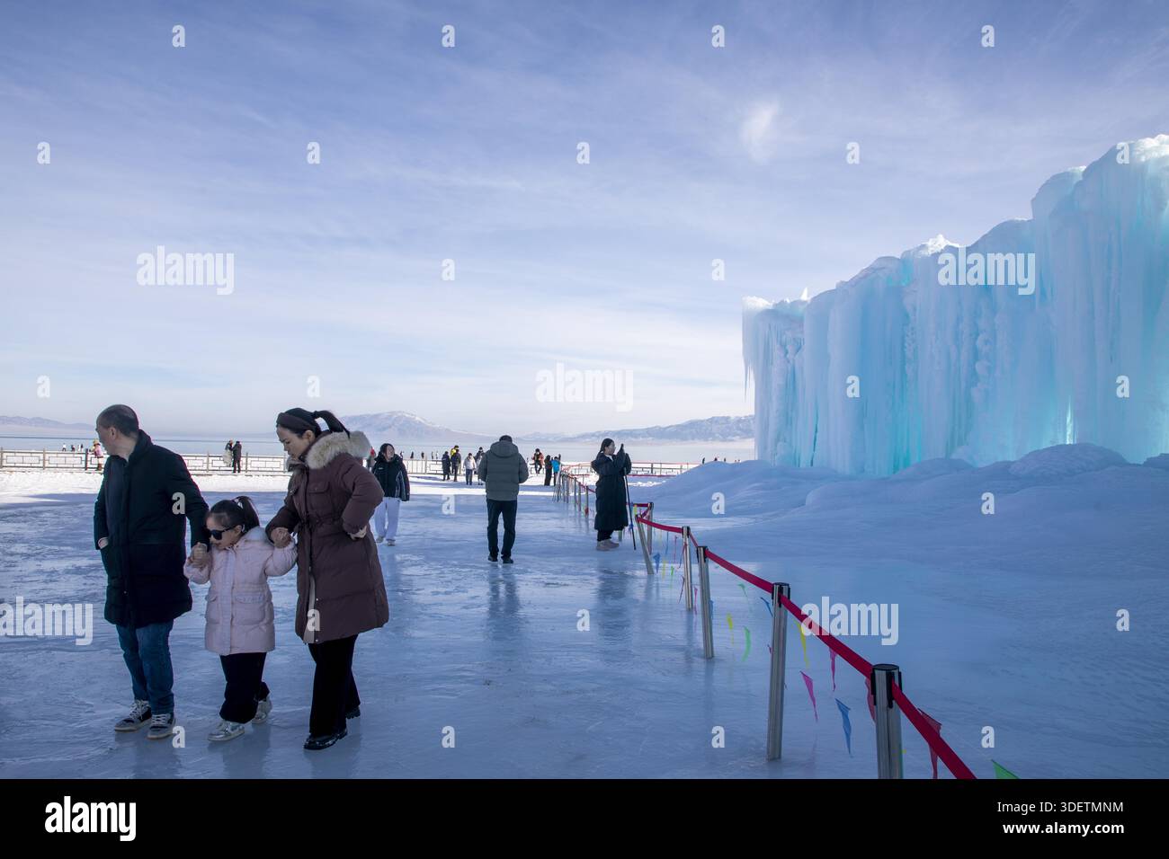 Tourists visit the blue ice waterfalls formed by frozen lake water at ...