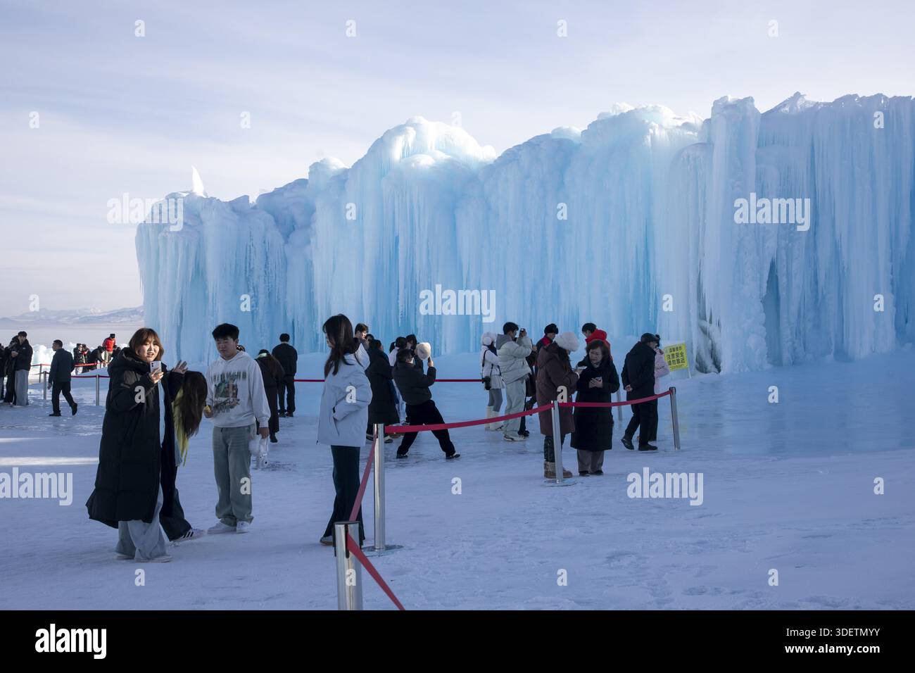 Tourists visit the blue ice waterfalls formed by frozen lake water at ...