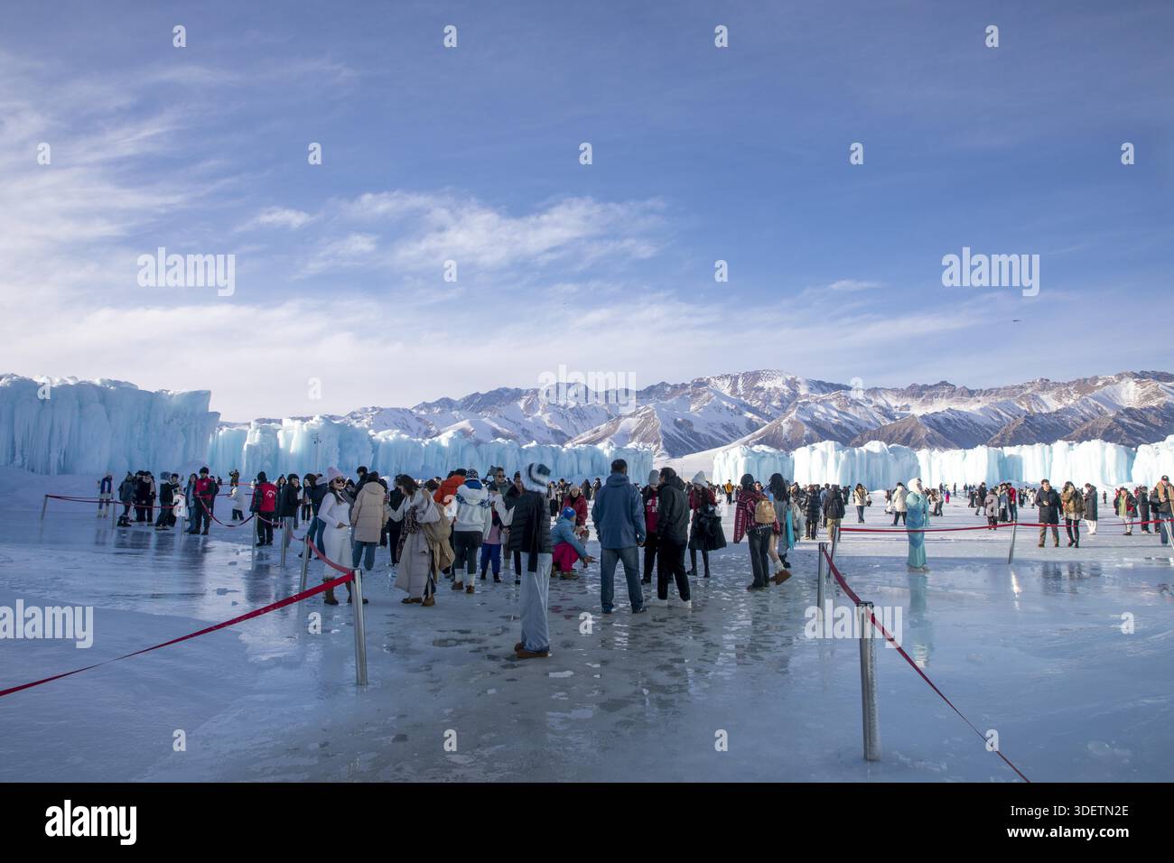 Tourists visit the blue ice waterfalls formed by frozen lake water at ...