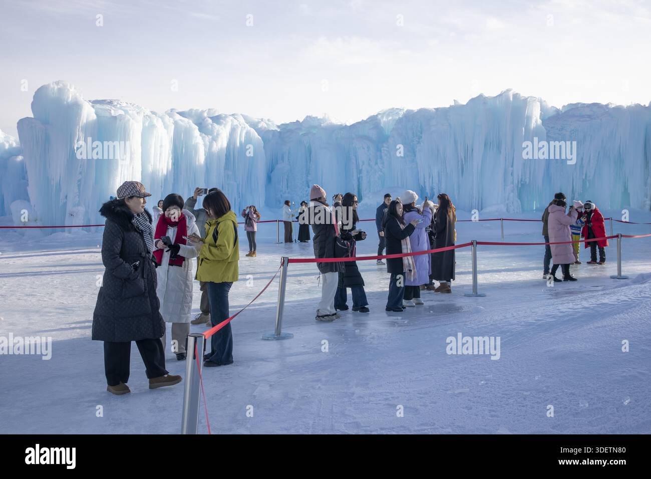 Tourists visit the blue ice waterfalls formed by frozen lake water at ...