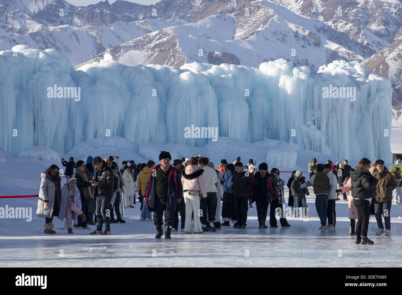 Tourists visit the blue ice waterfalls formed by frozen lake water at ...