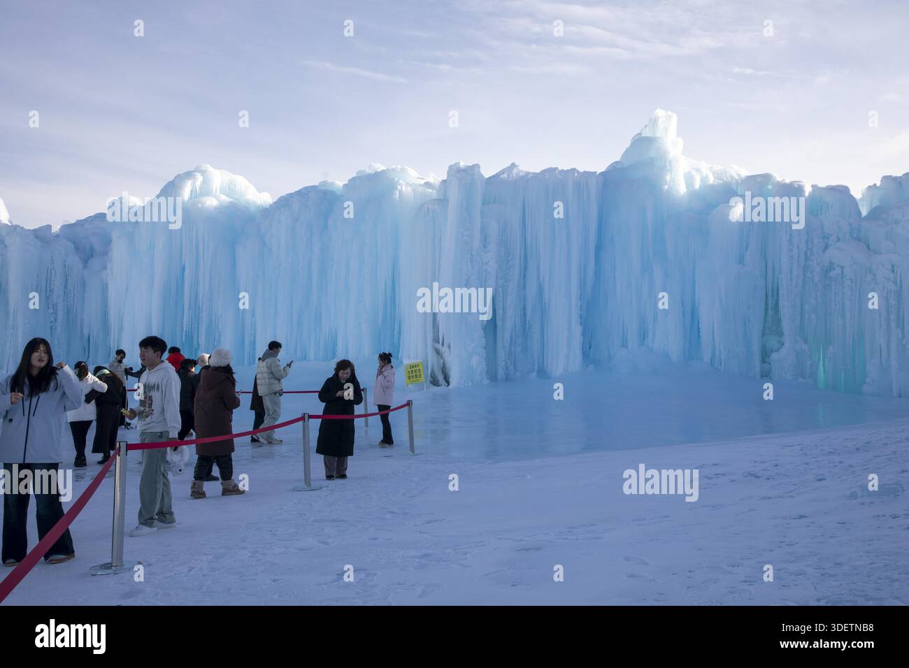 Tourists visit the blue ice waterfalls formed by frozen lake water at ...