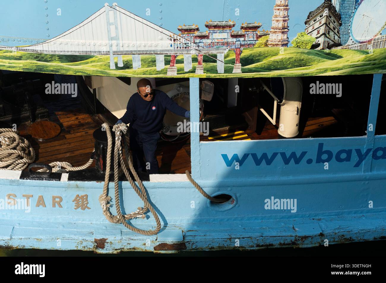 A man secures a rope on the Star Ferry in Hong Kong, showcasing the ...