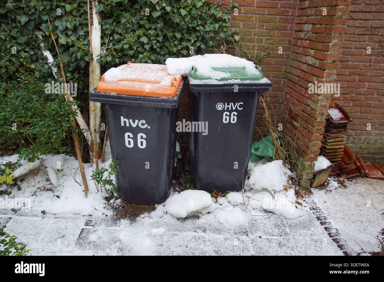 Two containers, bins in the snow for plastic waste and for green waste ...