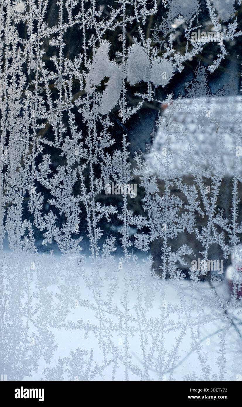 ice crystals form an intricate pattern on inside of glass window during ...