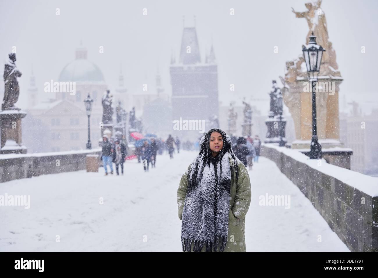 A woman crosses the medieval Charles Bridge during a heavy snowfall in ...