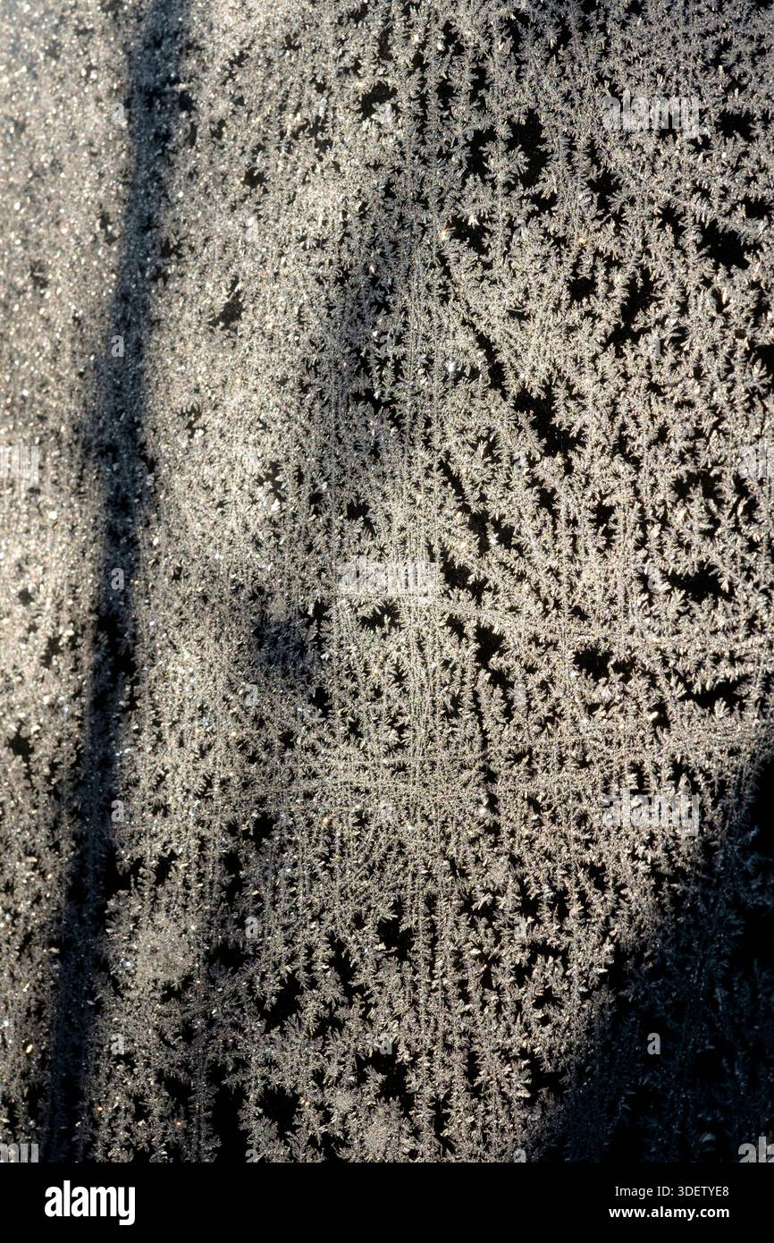 ice crystals form an intricate pattern on inside of glass window during ...