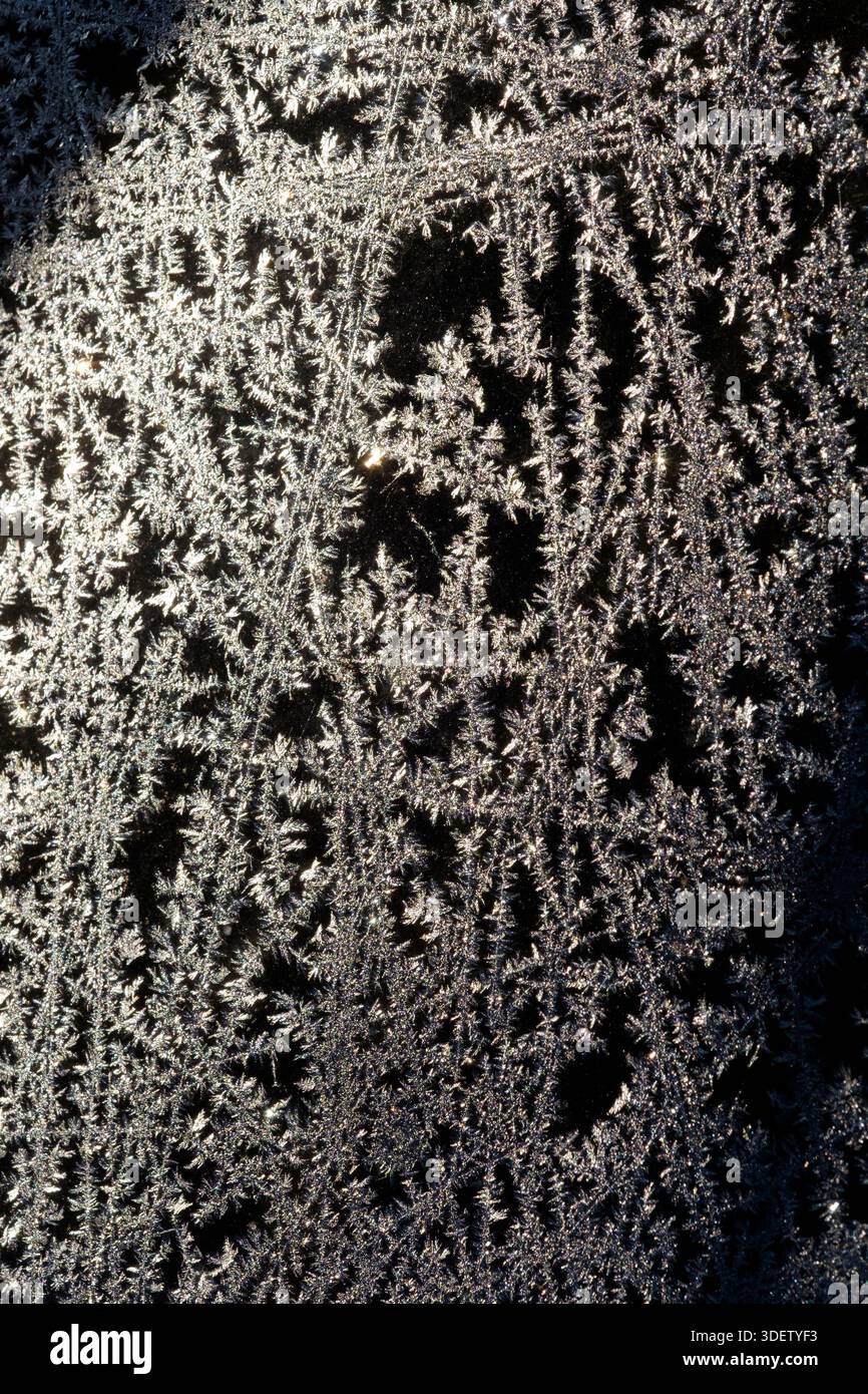 ice crystals form an intricate pattern on inside of glass window during ...