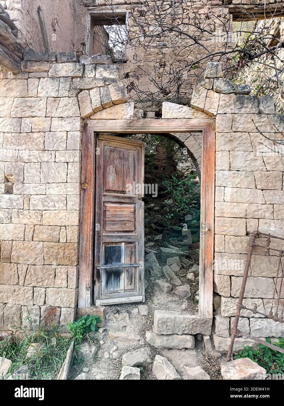 A wooden door is open in front of a stone wall. The door is wooden and ...
