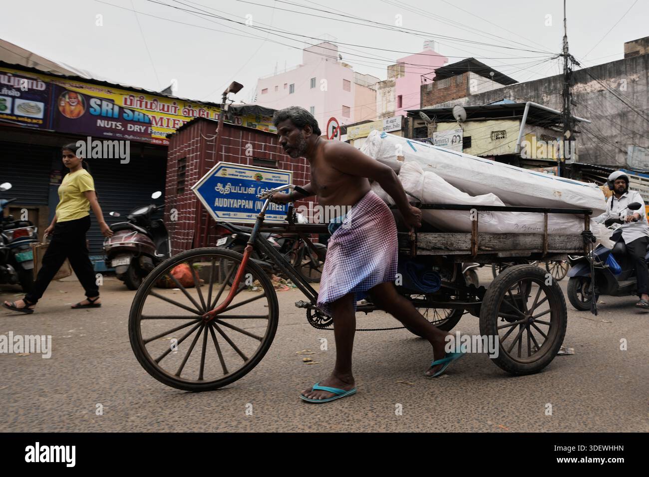 A laborer pulls a load on his rickshaw at a market in Chennai, India ...