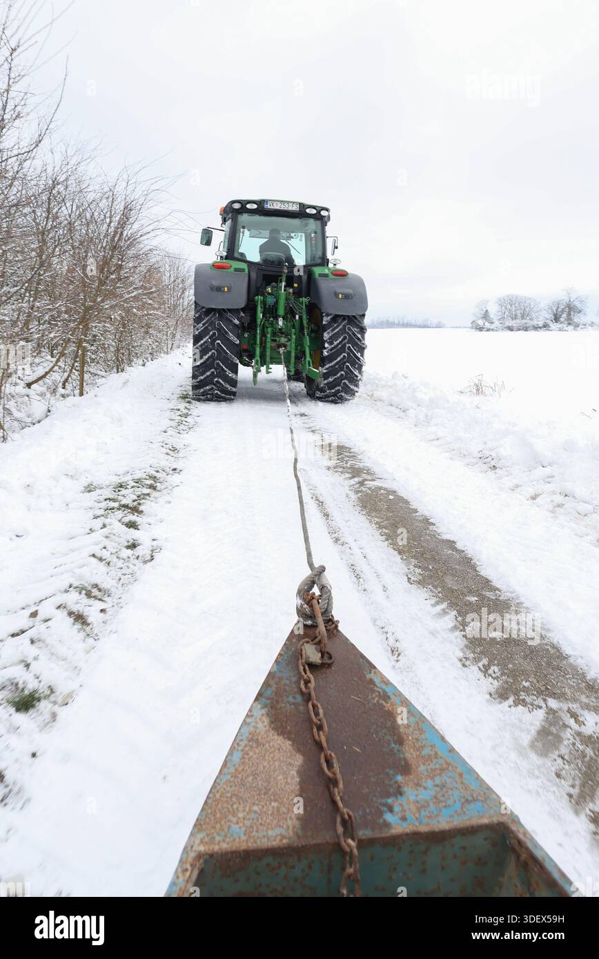 A tractor pulls people on a boat sled at snow covered field in Vinkovci ...