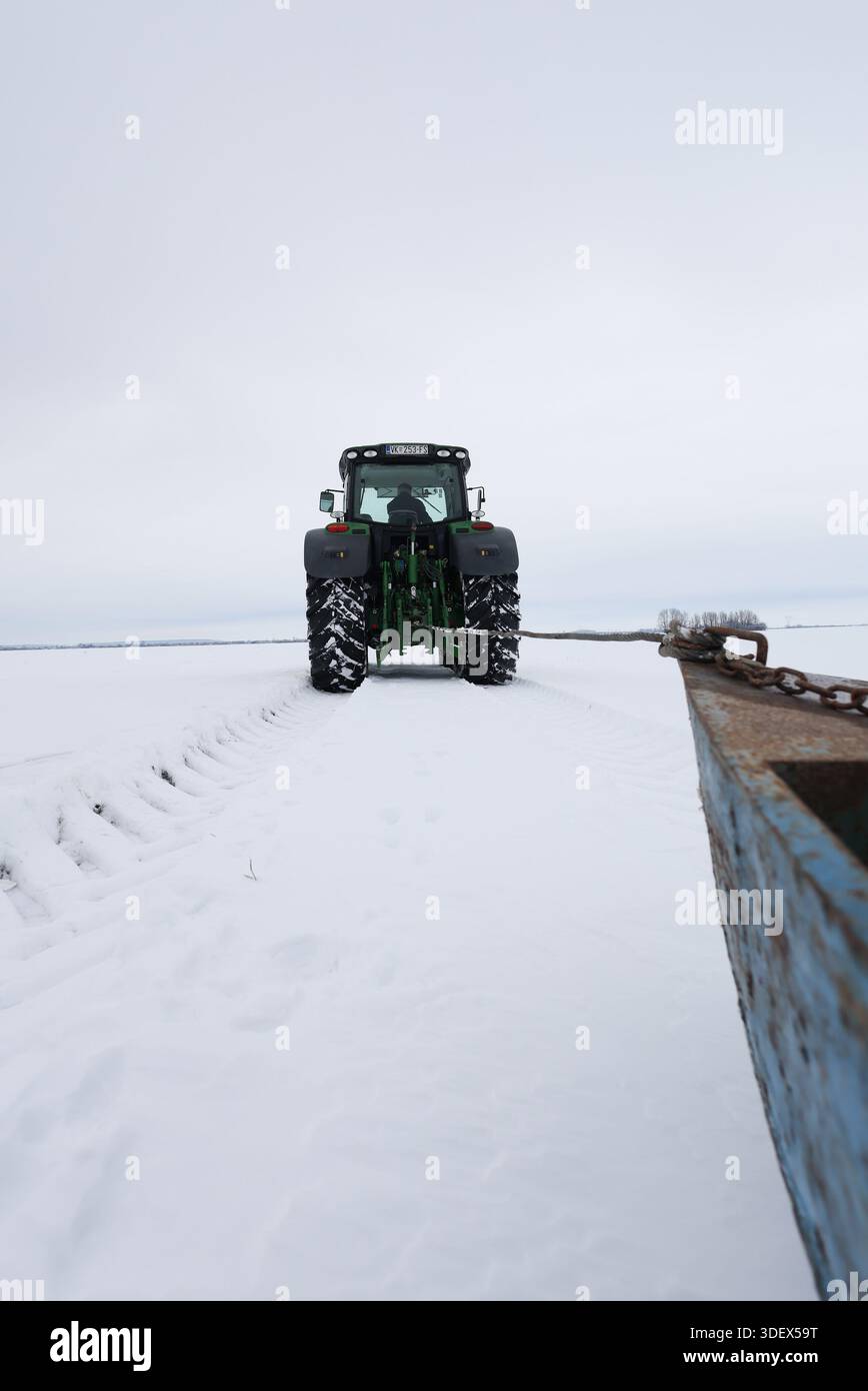 A tractor pulls people on a boat sled at snow covered field in Vinkovci ...