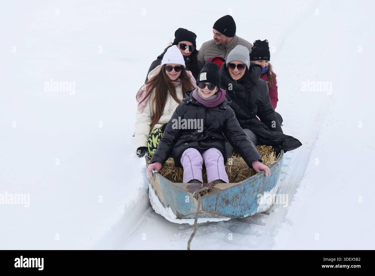 A tractor pulls people on a boat sled at snow covered field in Vinkovci ...