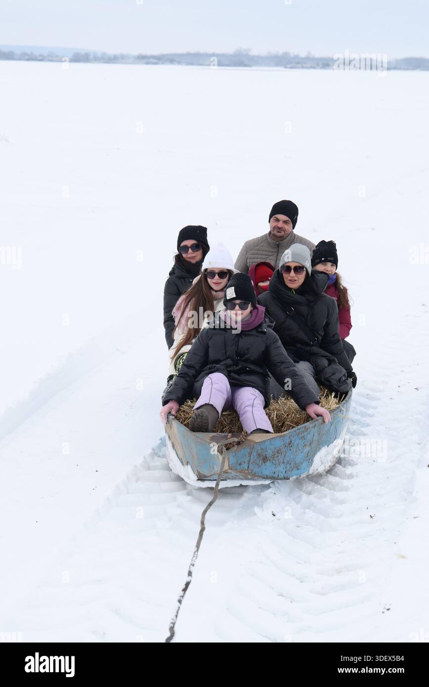 A tractor pulls people on a boat sled at snow covered field in Vinkovci ...