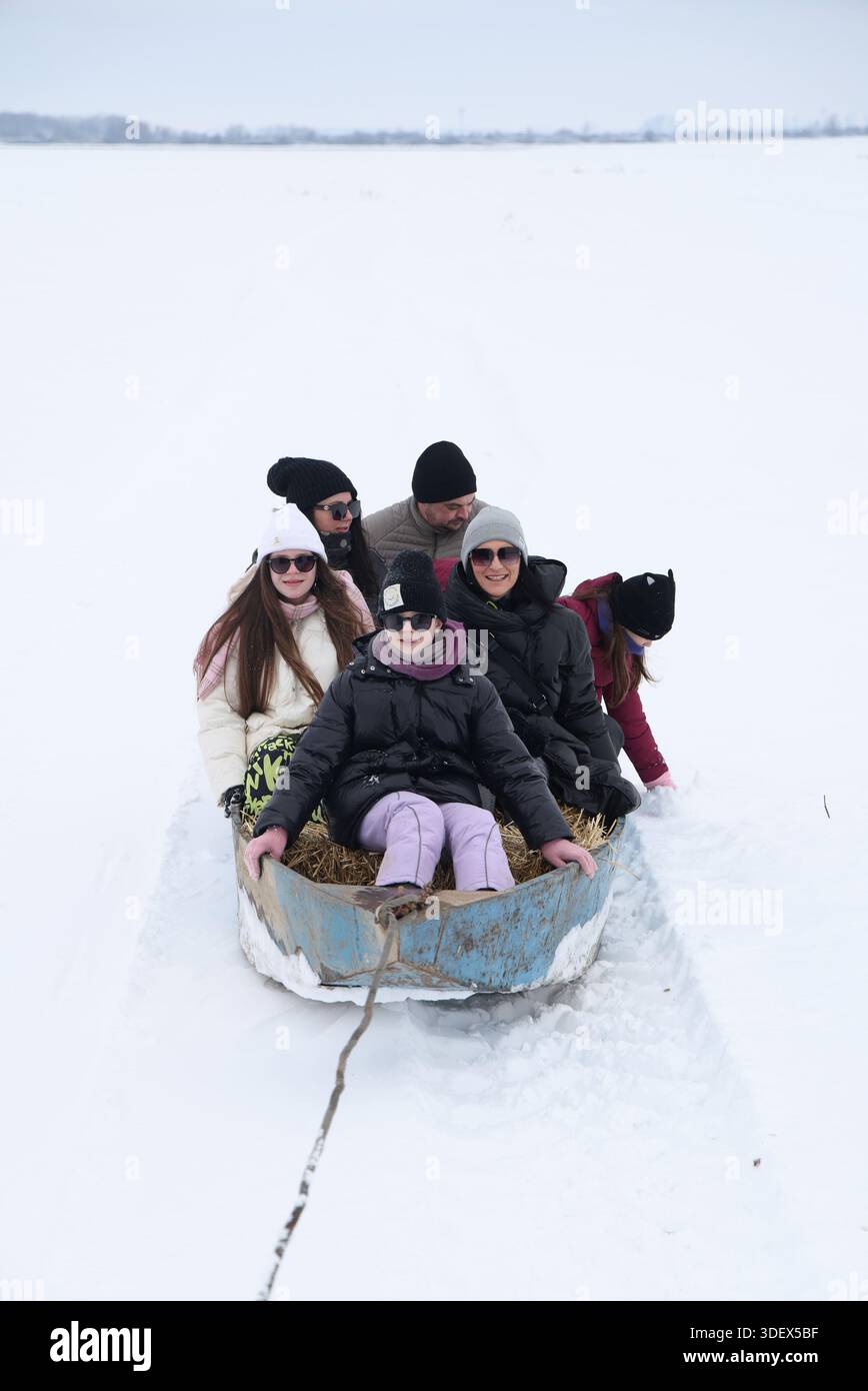 A tractor pulls people on a boat sled at snow covered field in Vinkovci ...