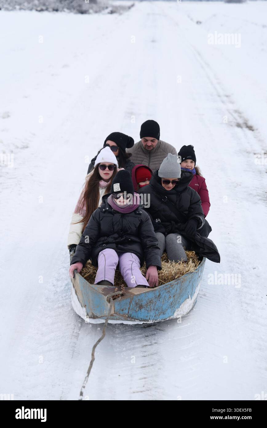 A tractor pulls people on a boat sled at snow covered field in Vinkovci ...