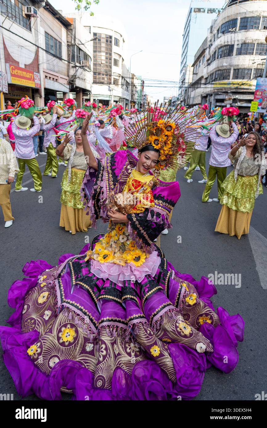 A Sinulog Festival dancer in a purple and gold costume with sunburst headdress performs during a ...