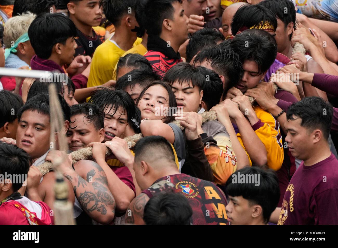 Catholic devotees pull a rope tied to the carriage carrying the image ...