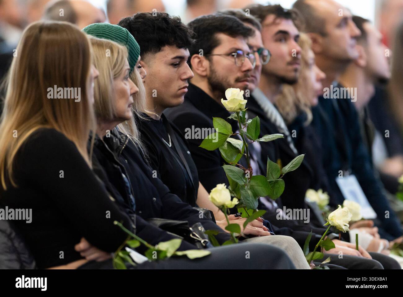Participants hold flowers during the official commemorative ceremony ...
