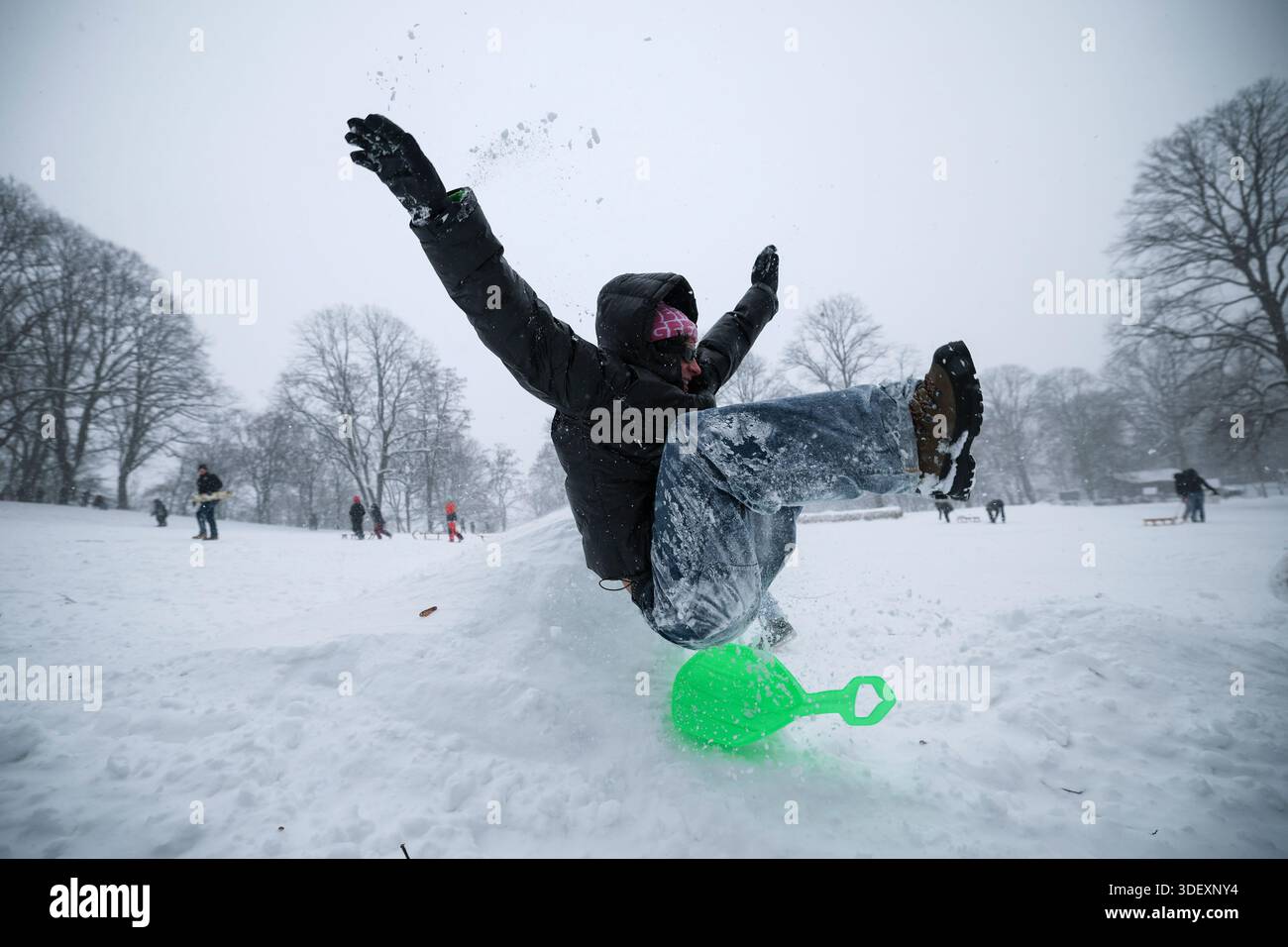 A person flies over a small jump in the snow-covered ski jump park in ...