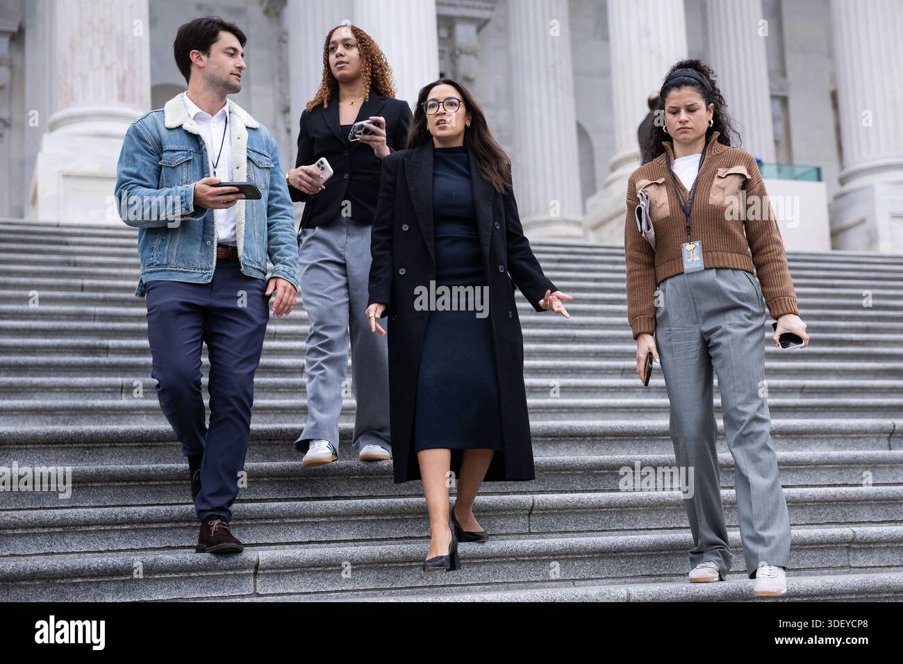 Rep. Alexandria Ocasio-Cortez (D-N.Y.) walks with a reporter and aides ...