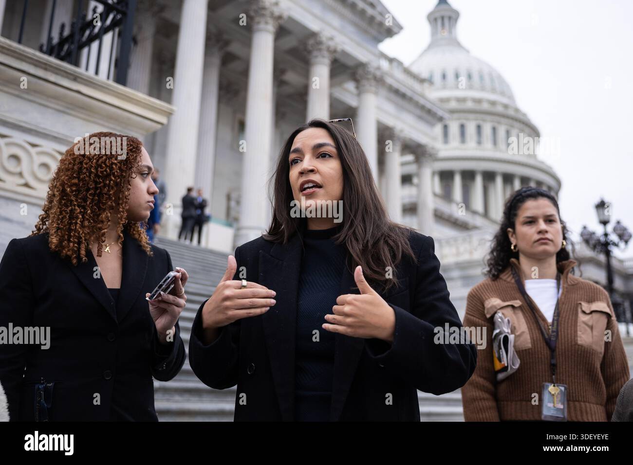 Rep. Alexandria Ocasio-Cortez (D-N.Y.), flanked by aides, speaks with a ...