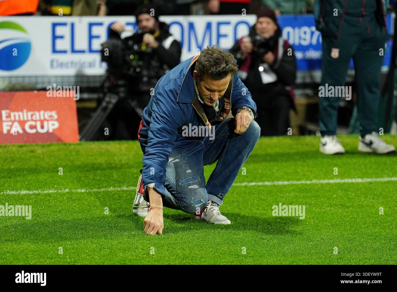 Wrexham co-owner Ryan Reynolds picks grass off the pitch ahead of the ...