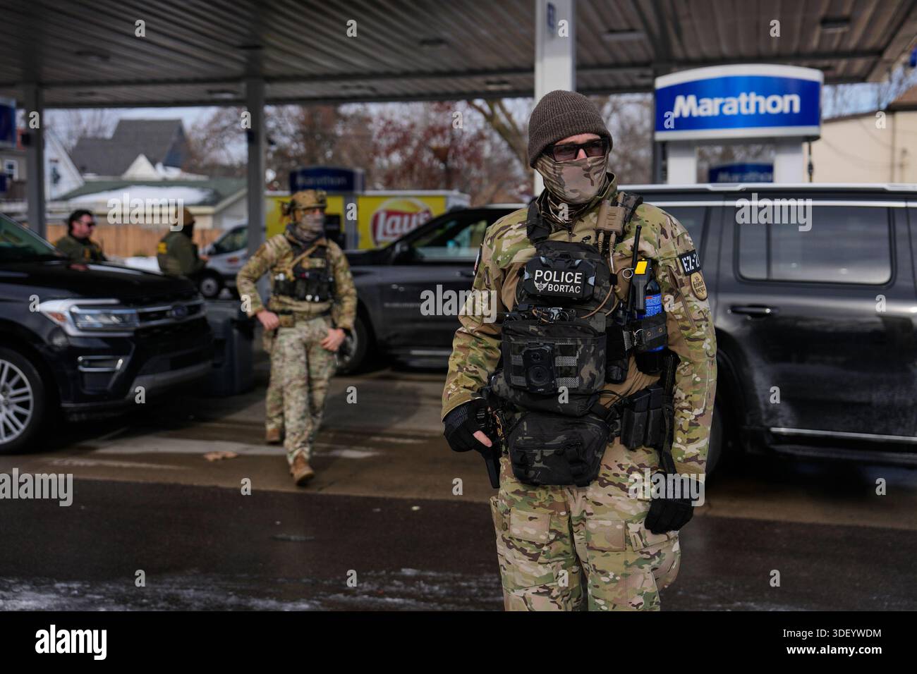 Federal law enforcement agents stand at a gas station while on patrol ...