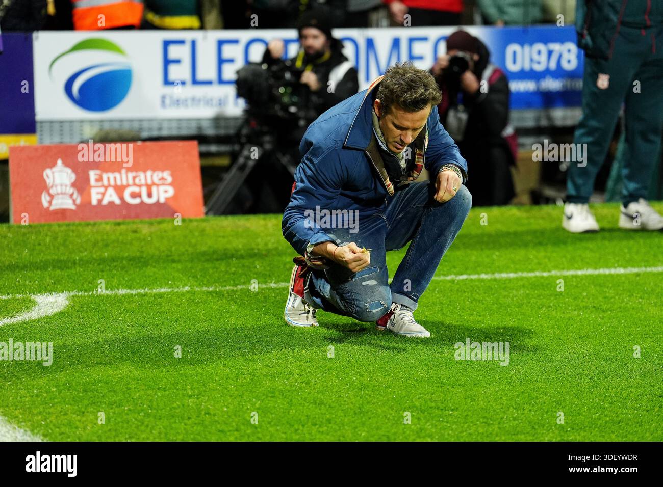 Wrexham co-owner Ryan Reynolds picks grass off the pitch ahead of the ...
