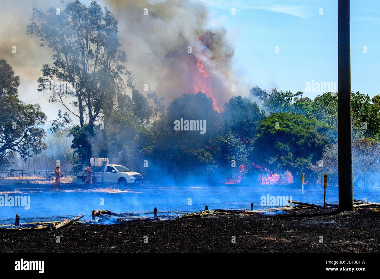 Firefighters work to black out an area around a house as flames catch ...