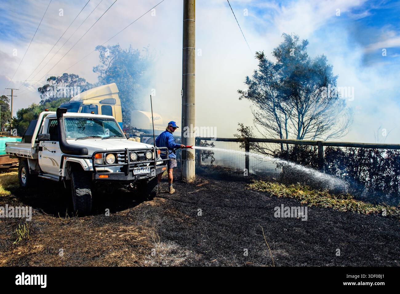 Residents use a water tanker trailer to fight spot fires threatening a ...