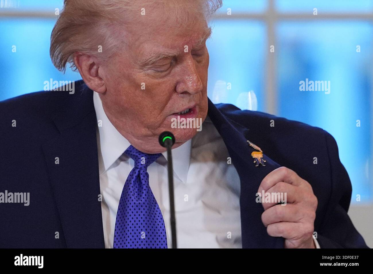 President Donald Trump talks about a pin on his suit lapel as he speaks ...