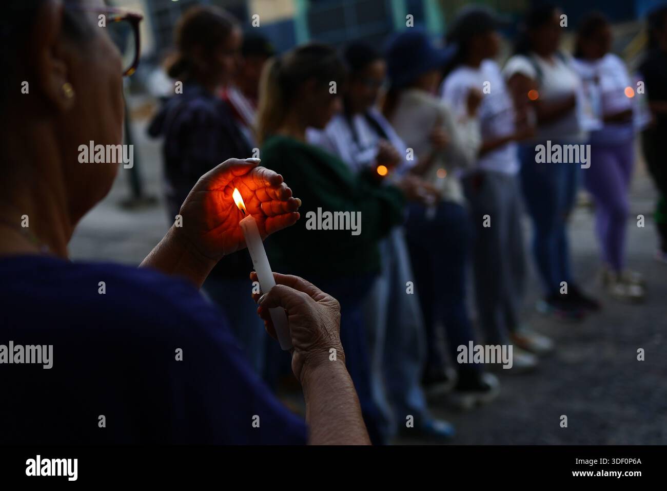 09 January 2026, Venezuela, Caracas: A woman holds a candle during a ...