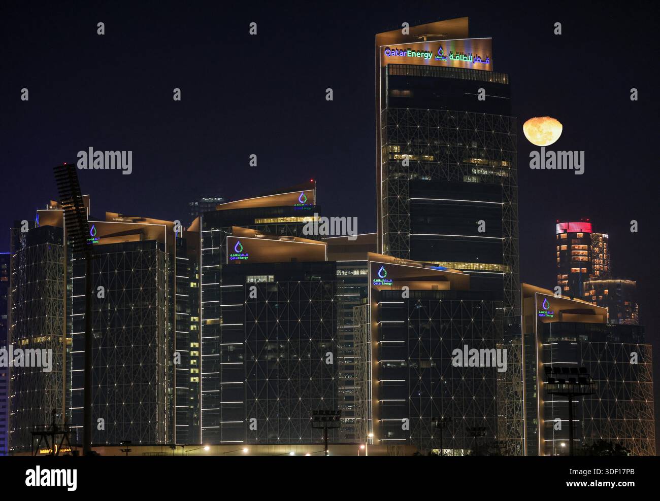 The moon appears next to the tower complex of Qatar Energy's ...