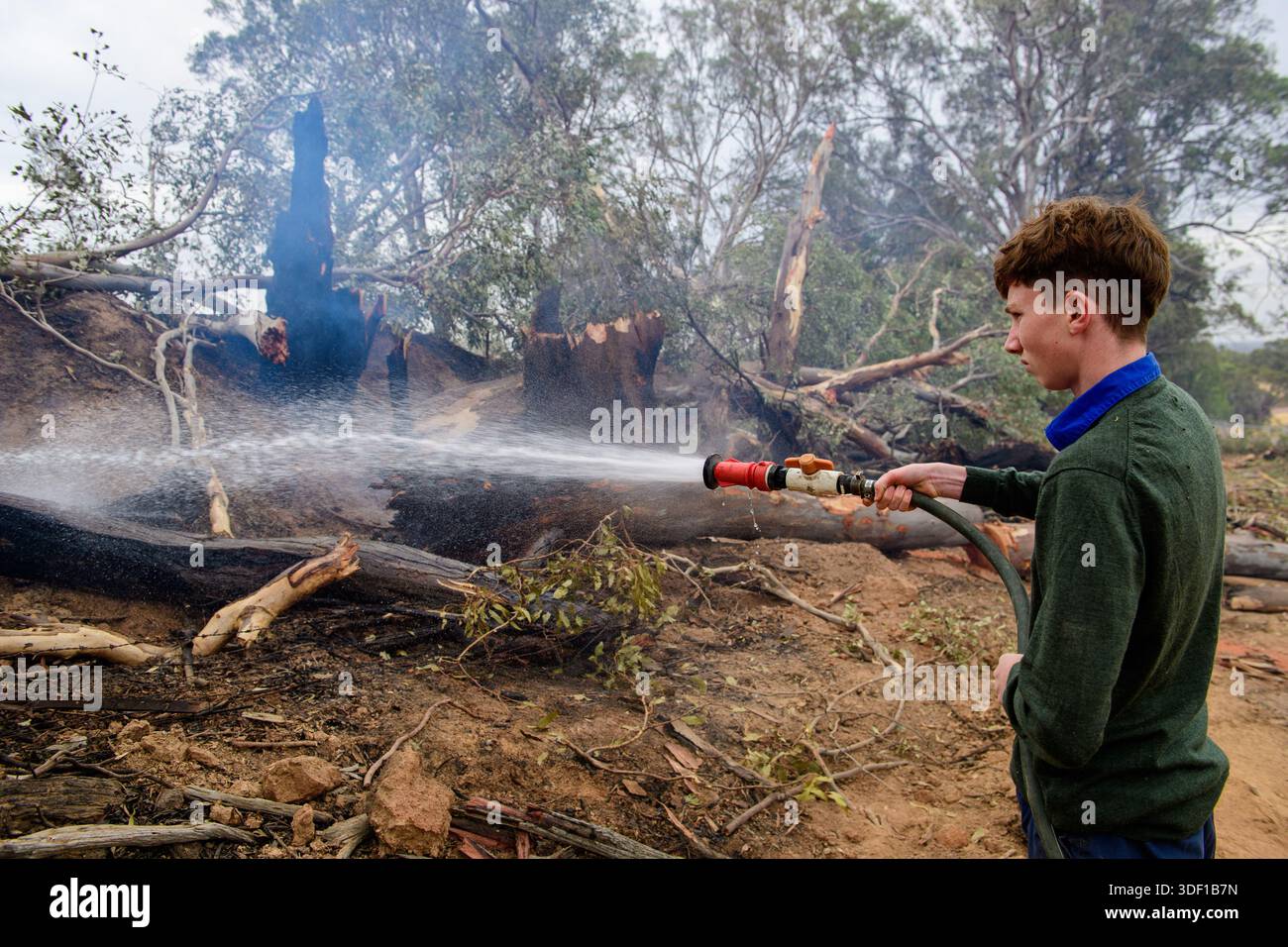 Year 11 student Max uses a fire hose to black out a burning log in ...