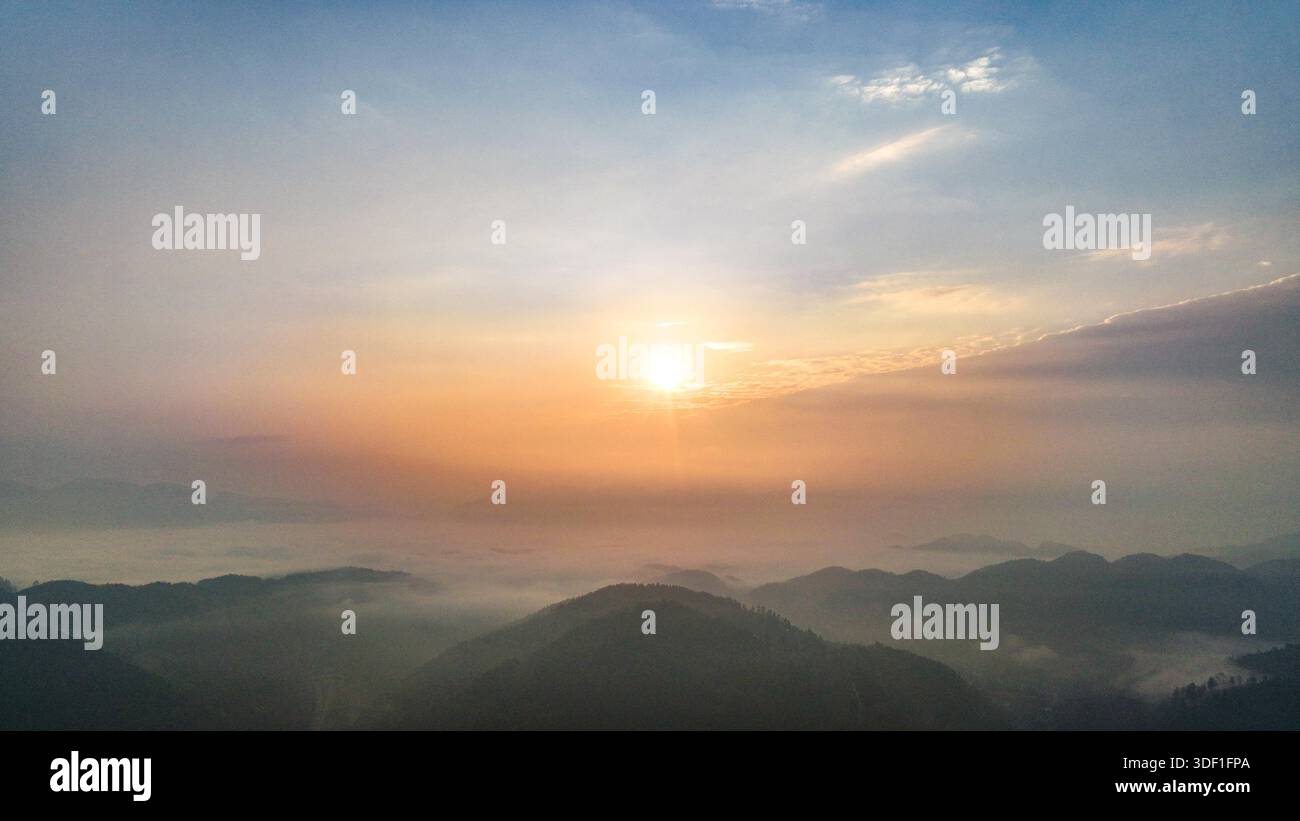 The morning sun rises over mountains as mist lingers in Dingshi Town ...